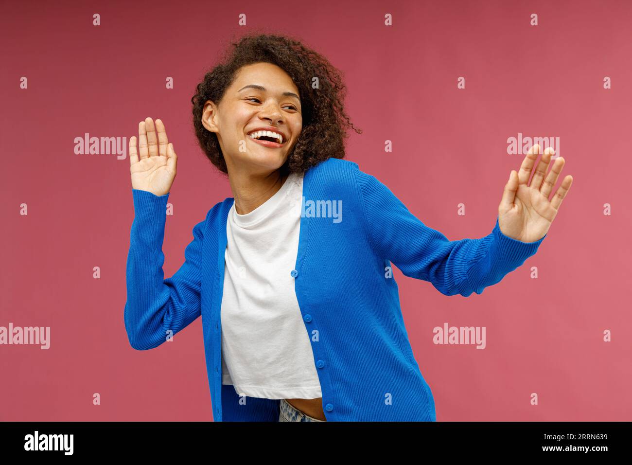 Happy woman in casual clothes dancing with raised hands while standing ...