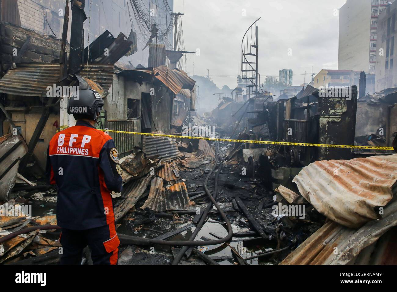 221229 -- MANILA, Dec. 29, 2022 -- A firefighter looks at charred homes ...