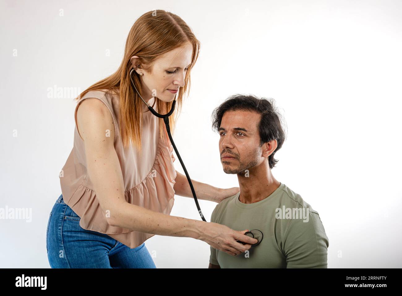 Young European doctor visiting an Asian man. Listening to his chest ...