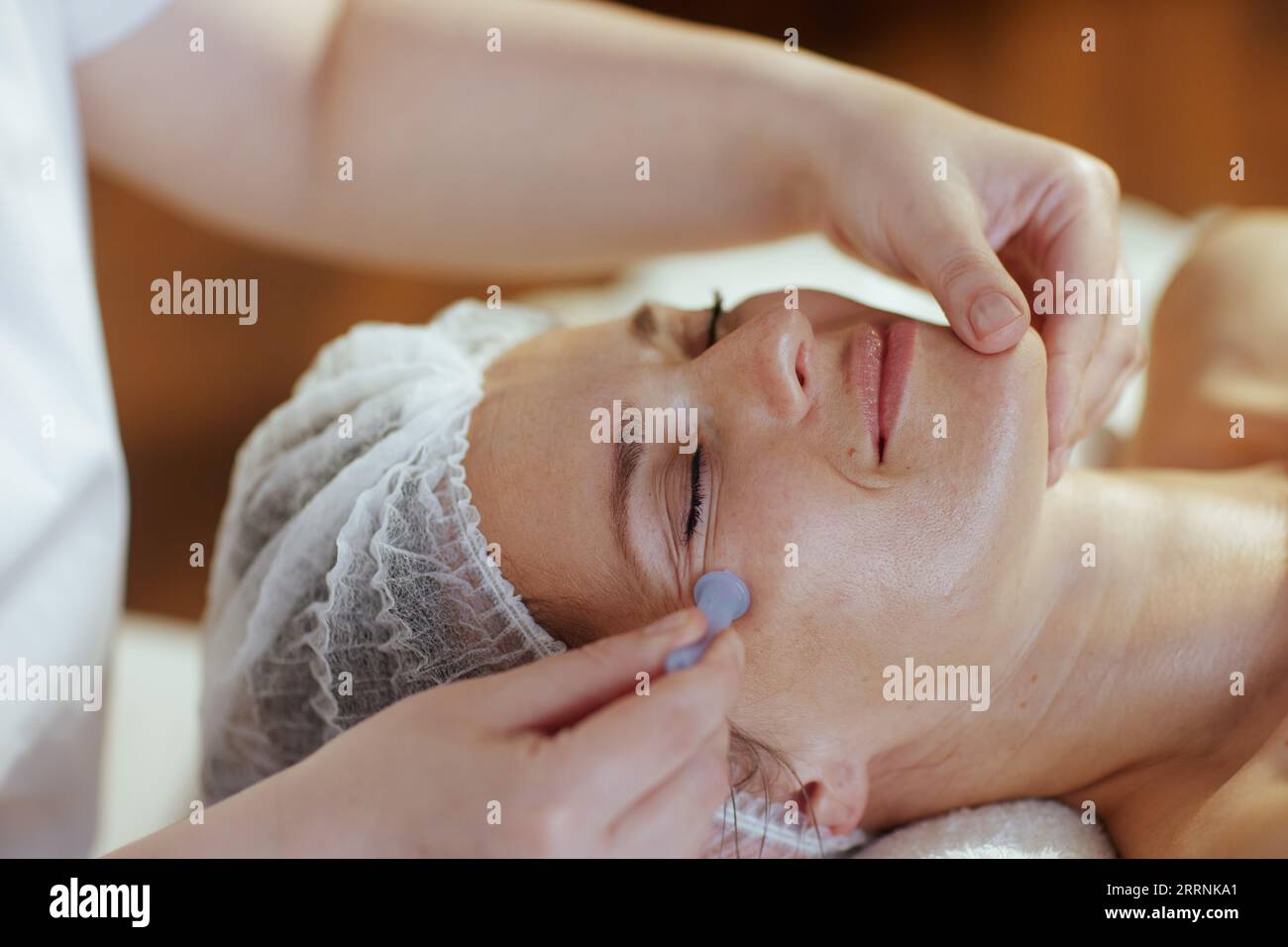 Healthcare time. massage therapist in spa salon with vacuum therapy cup massaging clients face ...