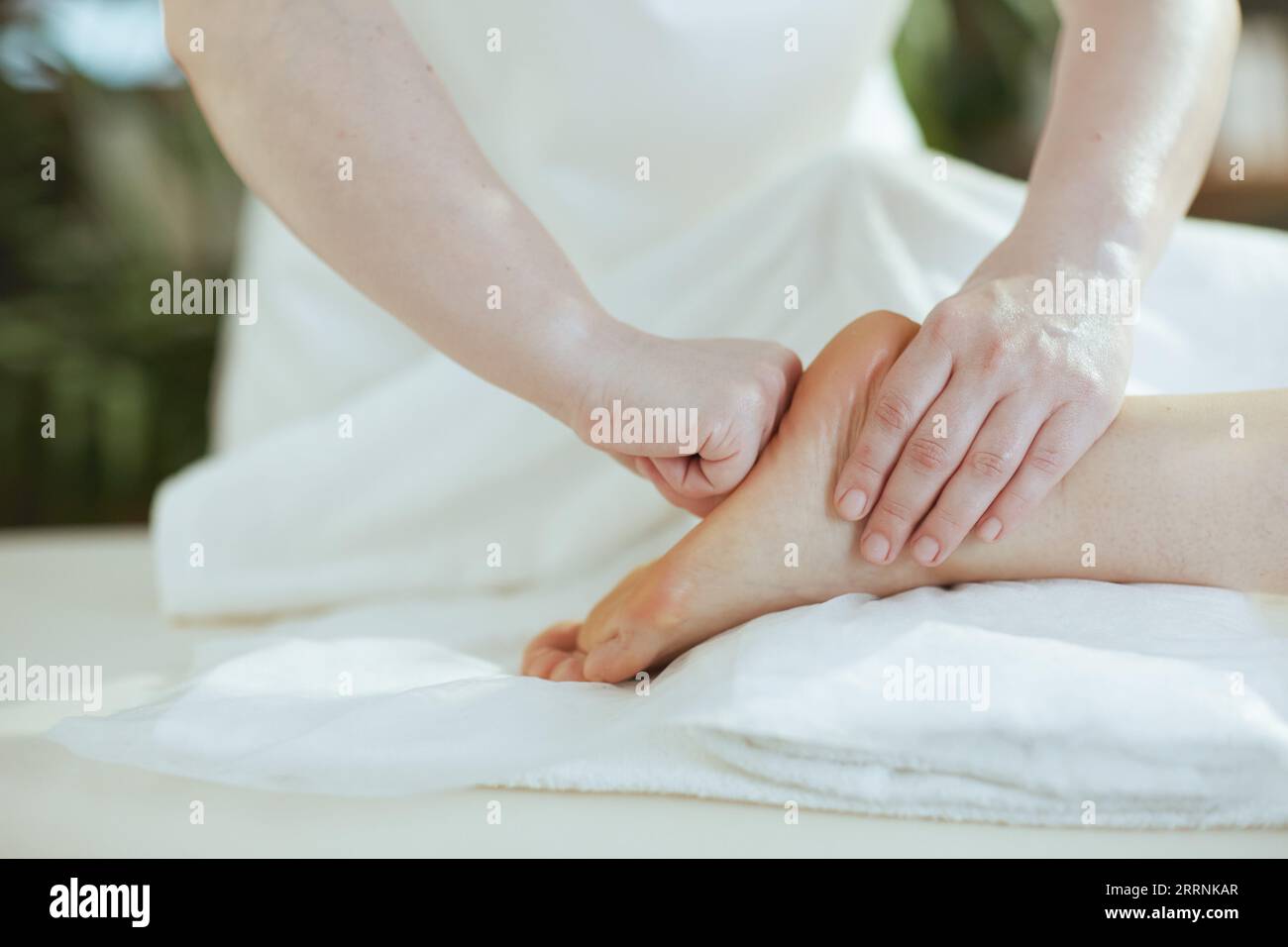 Healthcare time. Closeup on medical massage therapist in massage cabinet massaging clients foot ...