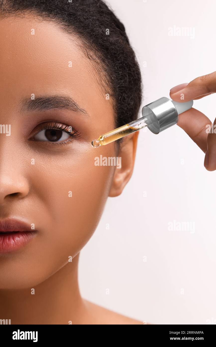 Woman applying serum onto her face on white background, closeup Stock ...