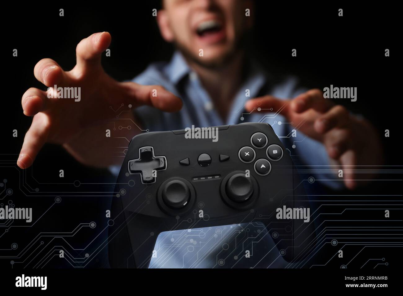 Gaming disorder. Emotional man reaching out for gamepad in darkness ...