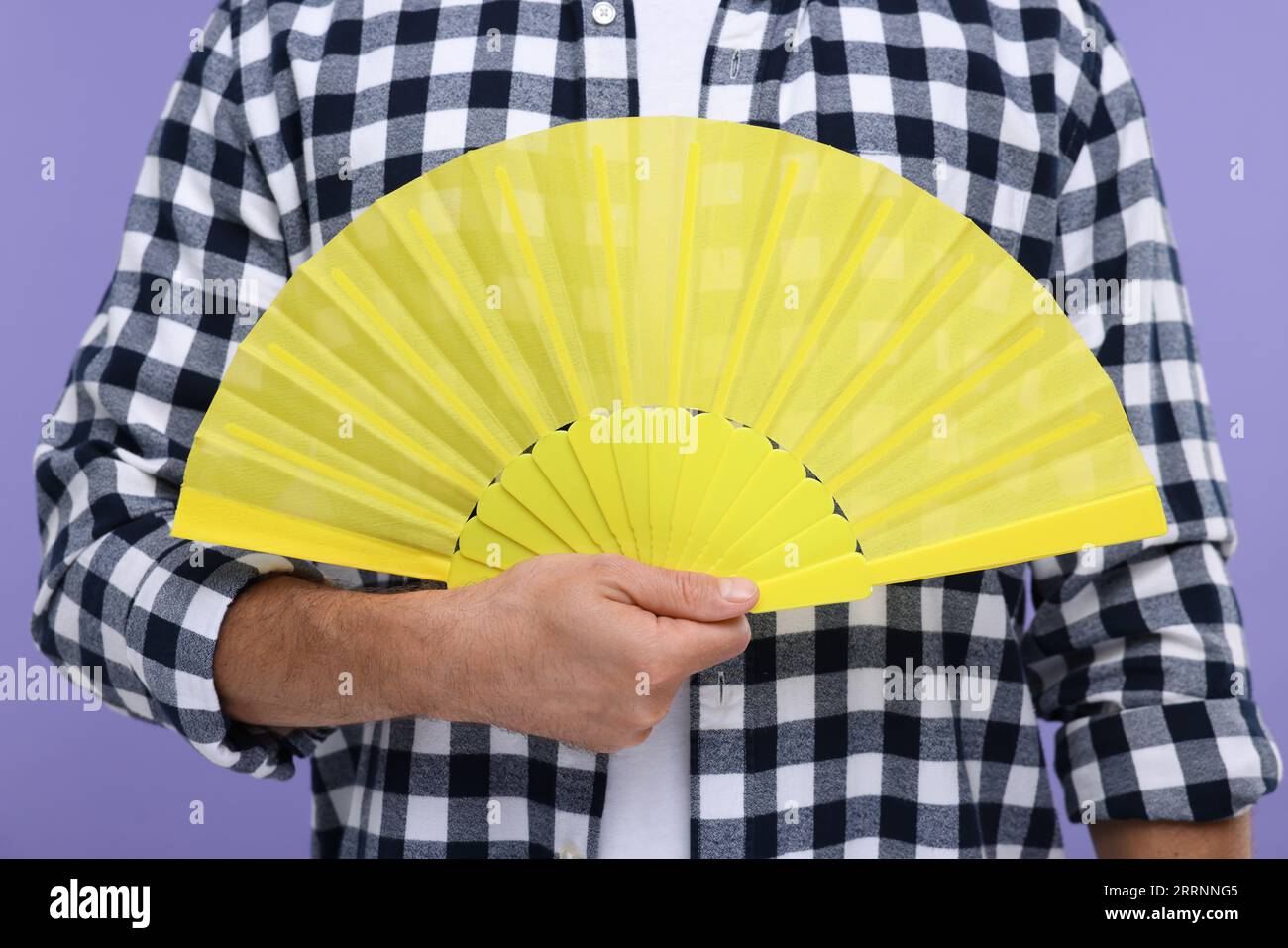 Man holding hand fan on purple background, closeup Stock Photo - Alamy
