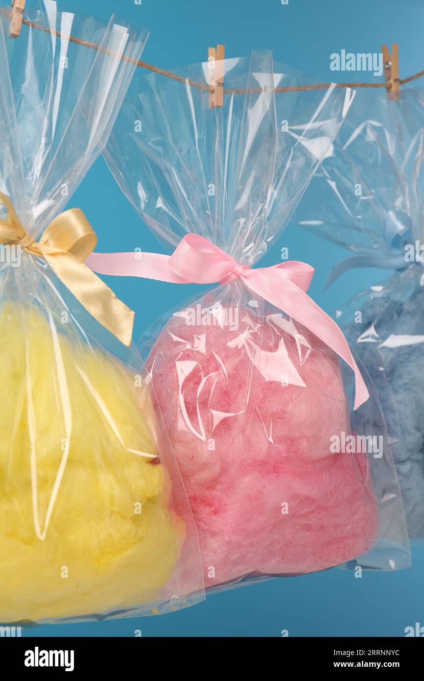 Packaged sweet cotton candies hanging on clothesline against light blue ...