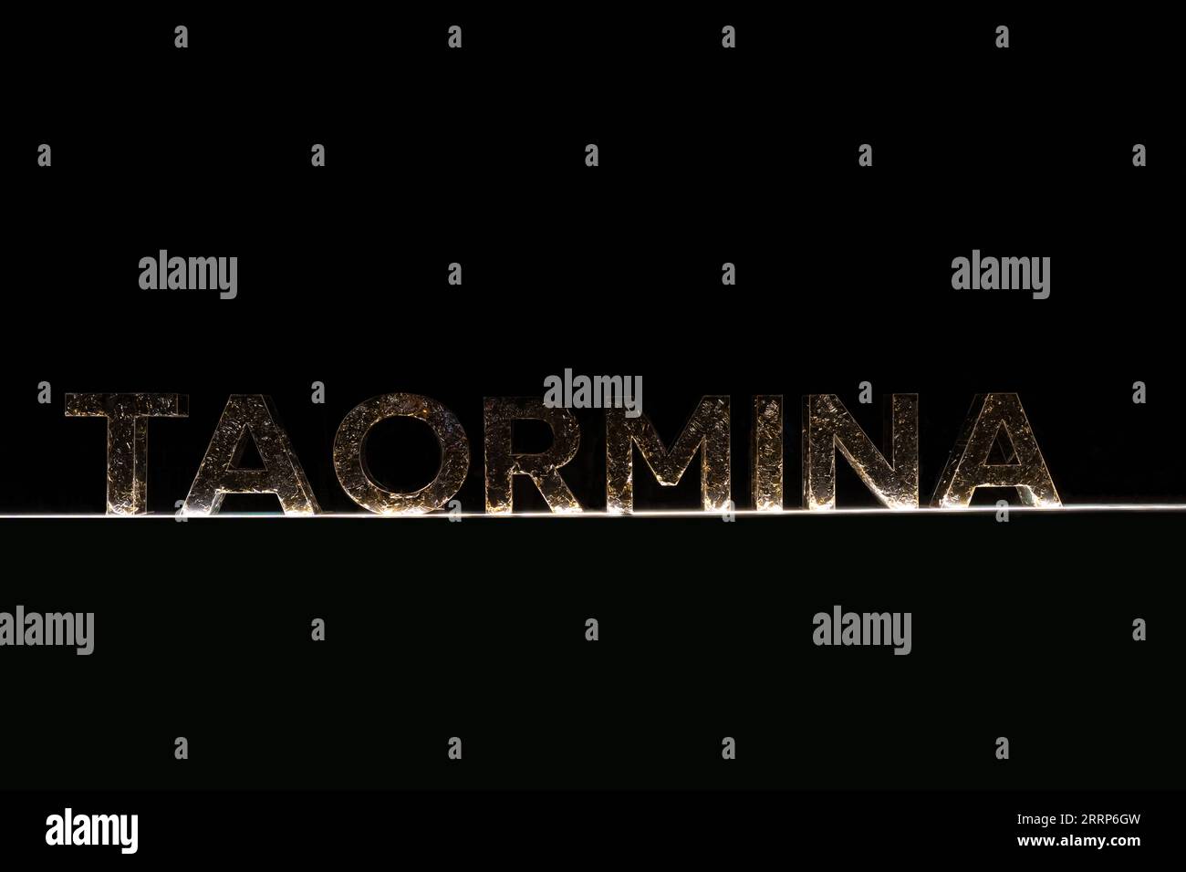 Glowing letters of sign Taormina on black background. Highlighted ...