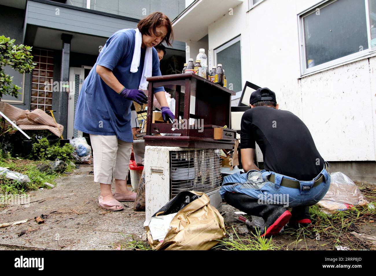 Residents tidy up their house flooded above the floor in Iwaki City ...