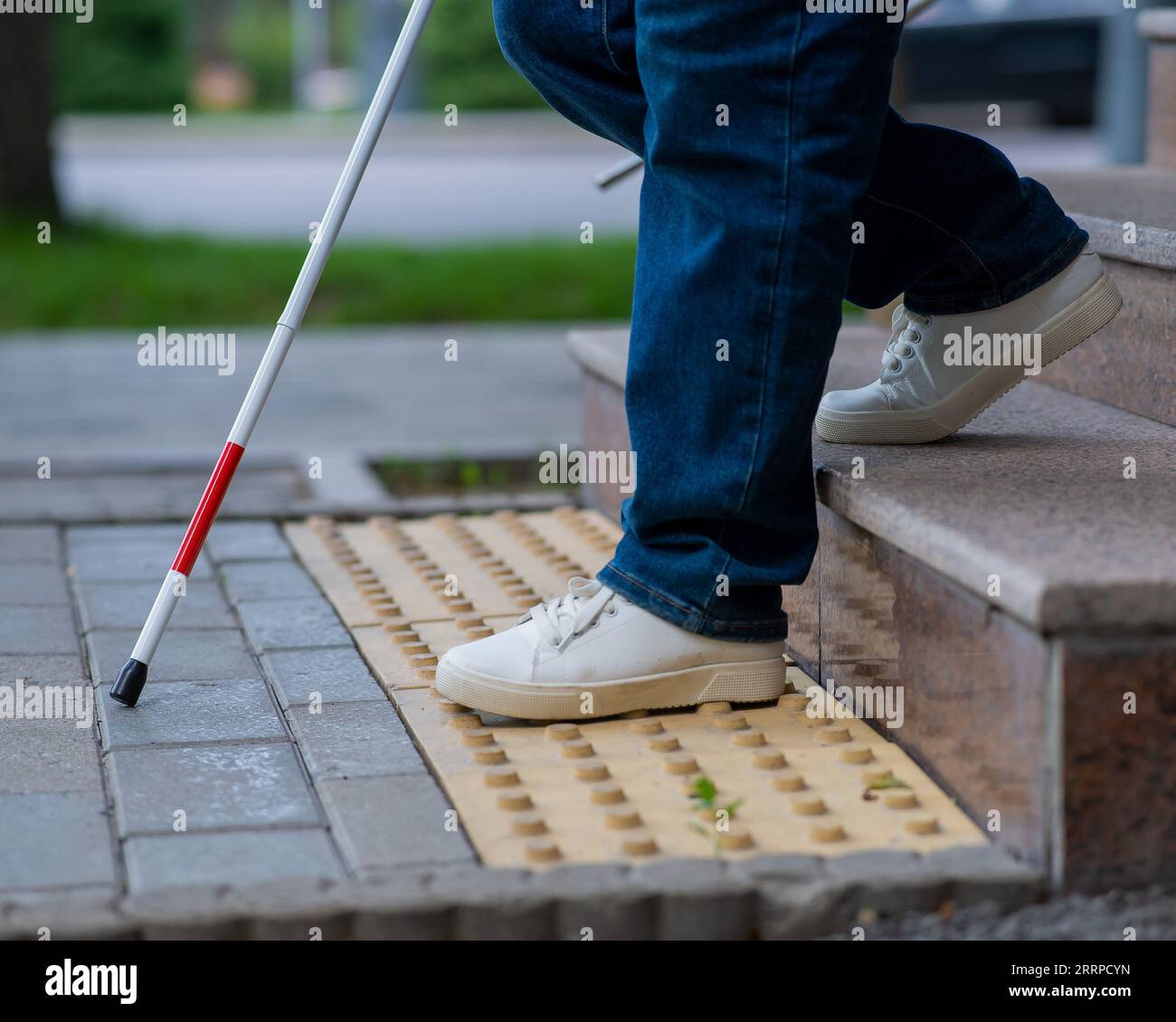 Close-up of female foot, walking stick and tactile tiles. Blind woman ...