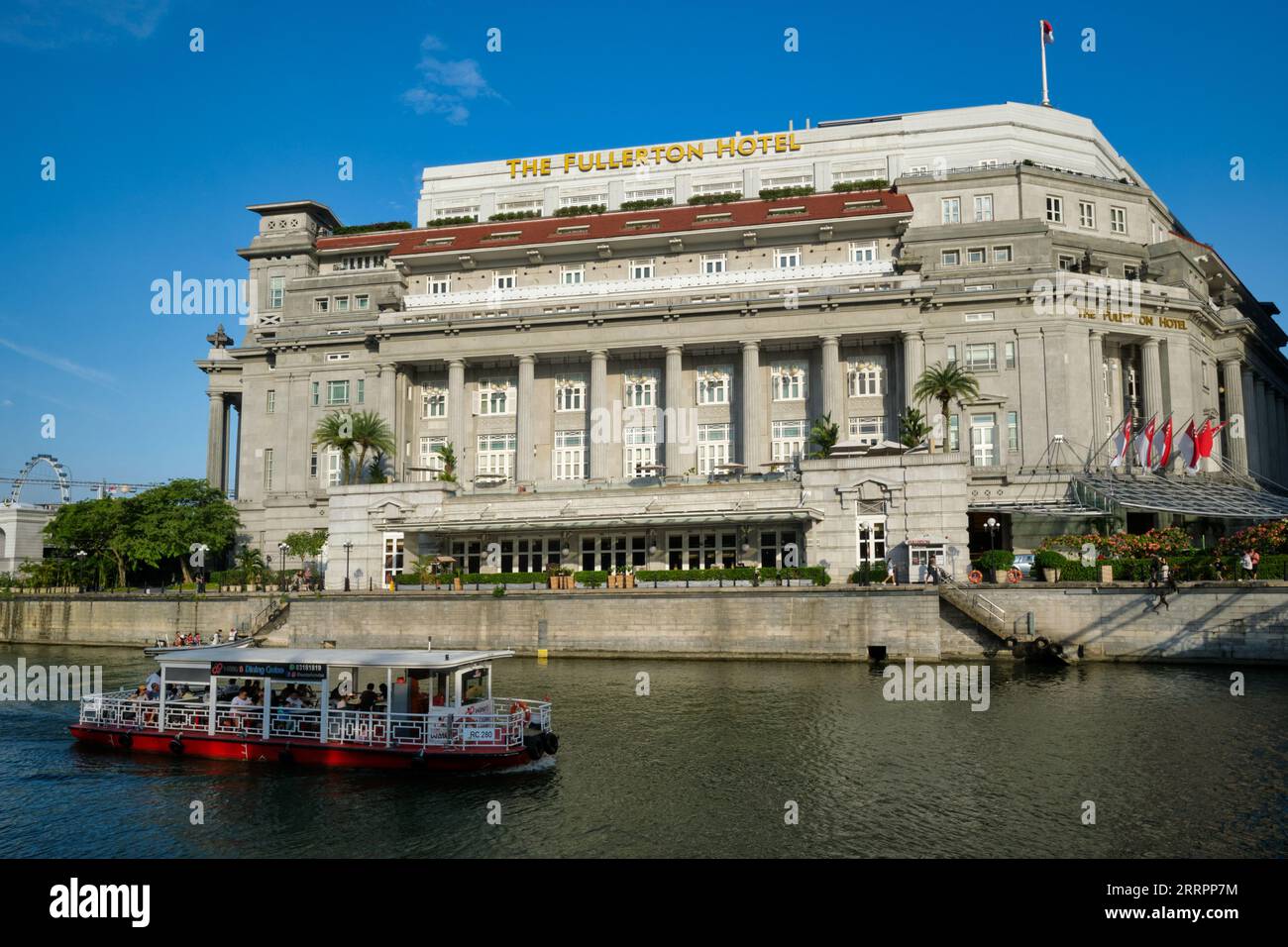An excursion boat on the Singapore River passes the rear side of ...