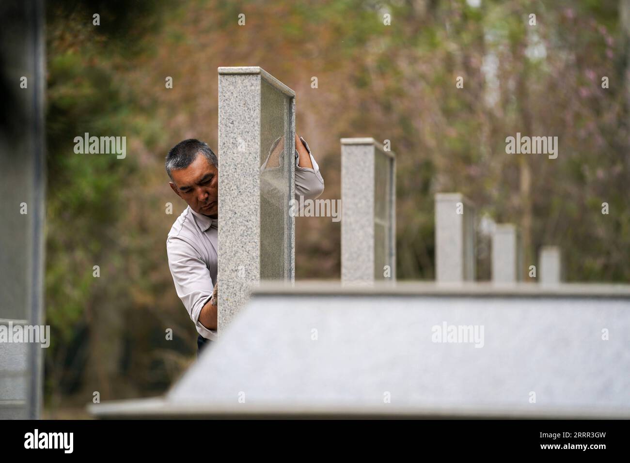 230430 -- YECHENG, April 30, 2023 -- Eniwar Emer wipes a tombstone in ...