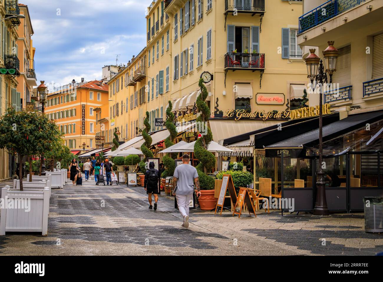 Nice, France - May 29, 2023: People walk by restaurants and bars on a ...