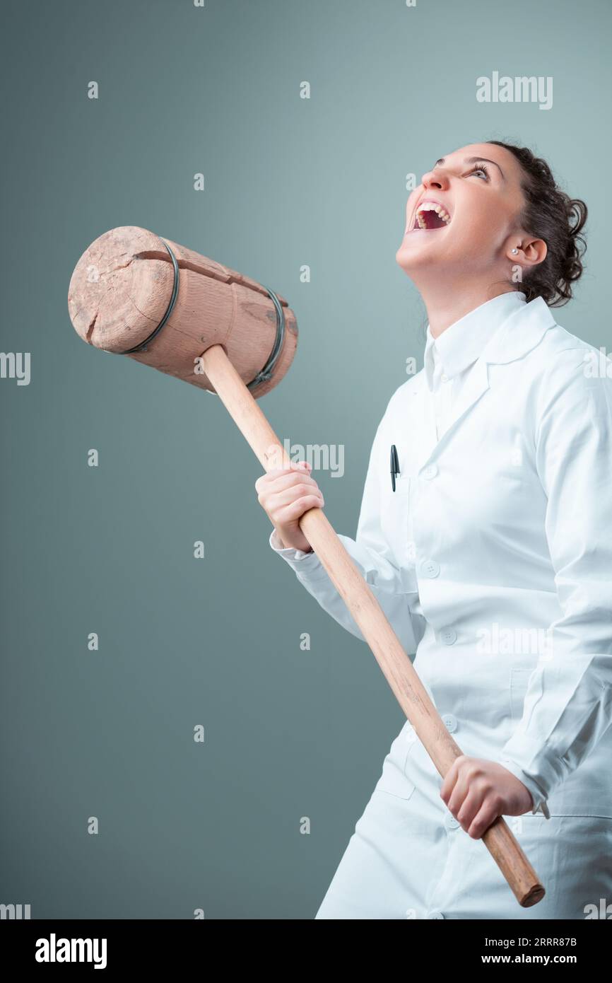 With a comedic twist, a scientist holds a hefty wooden mallet ...