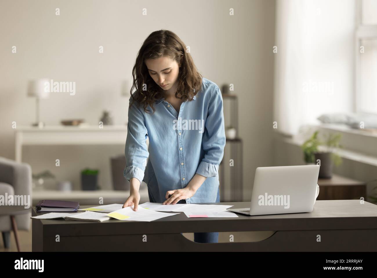 Focused gen Z business startup owner girl checking paper documents ...