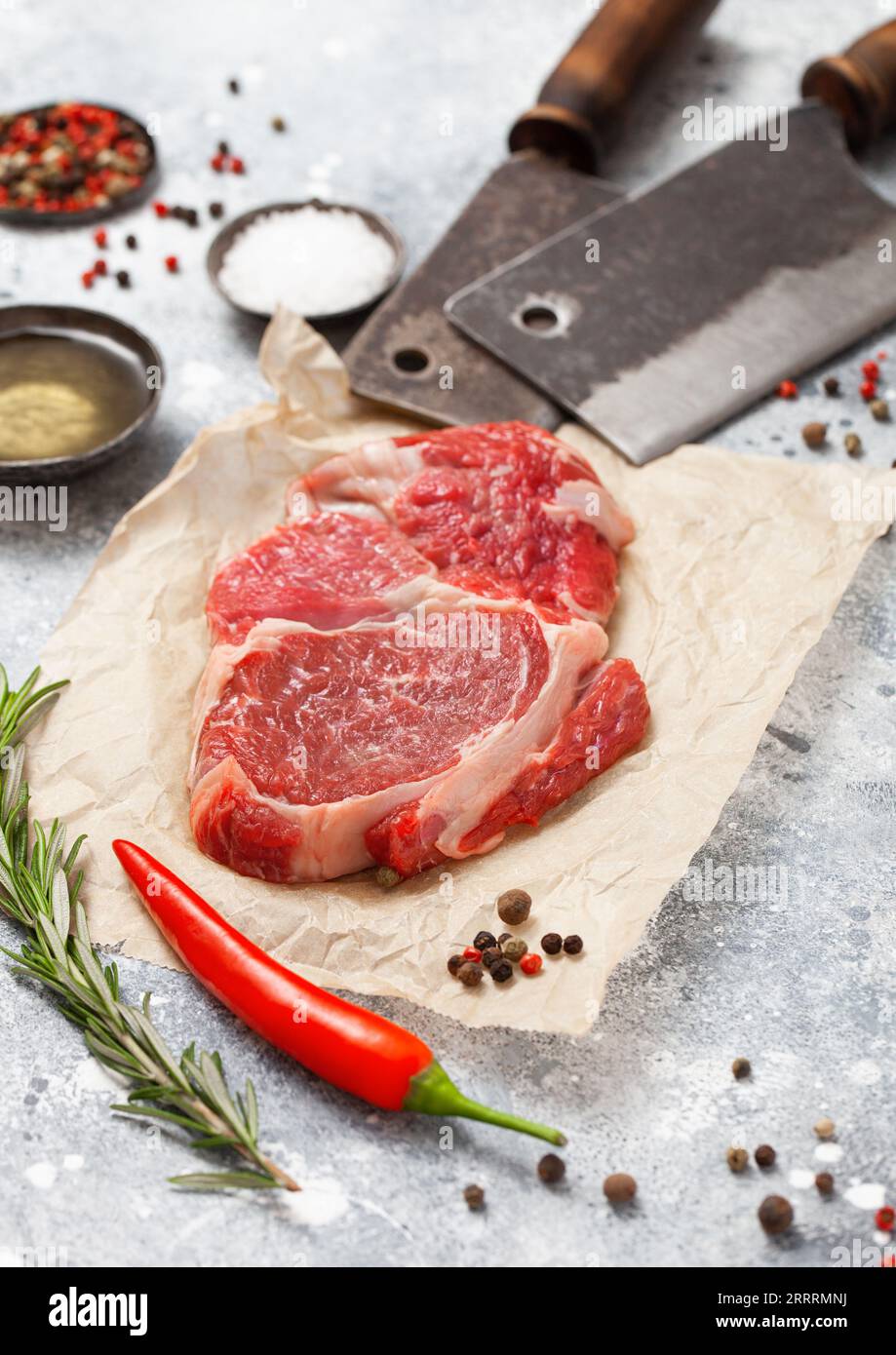 Red raw beef rib eye steak fillet with steel hatchets on light table ...