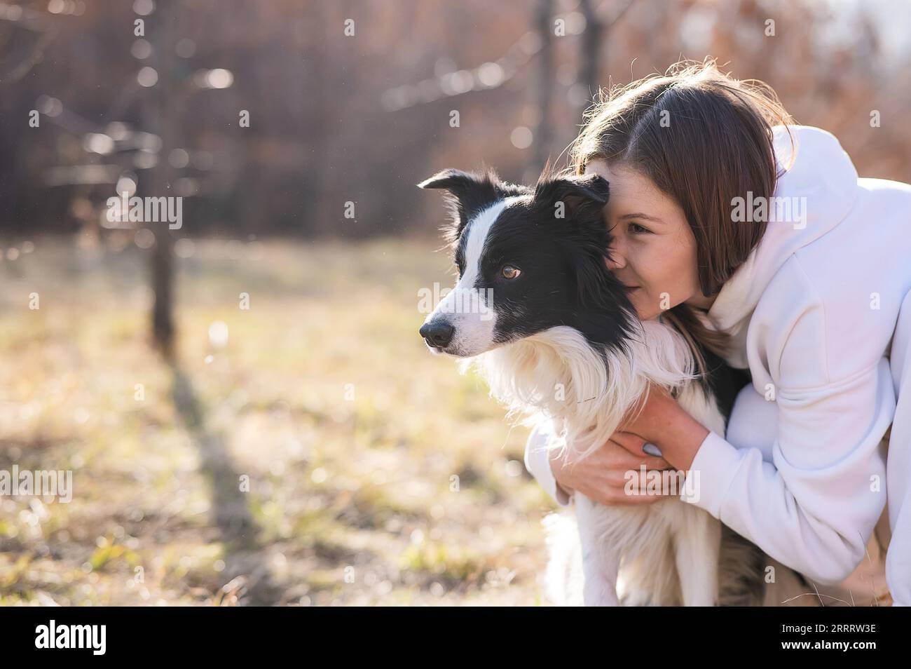 Caucasian woman hugging her dog Border Collie while sitting on a bench ...