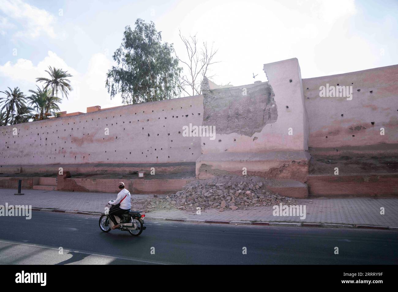 A man drives past a damaged wall of the historic Medina of Marrakech ...