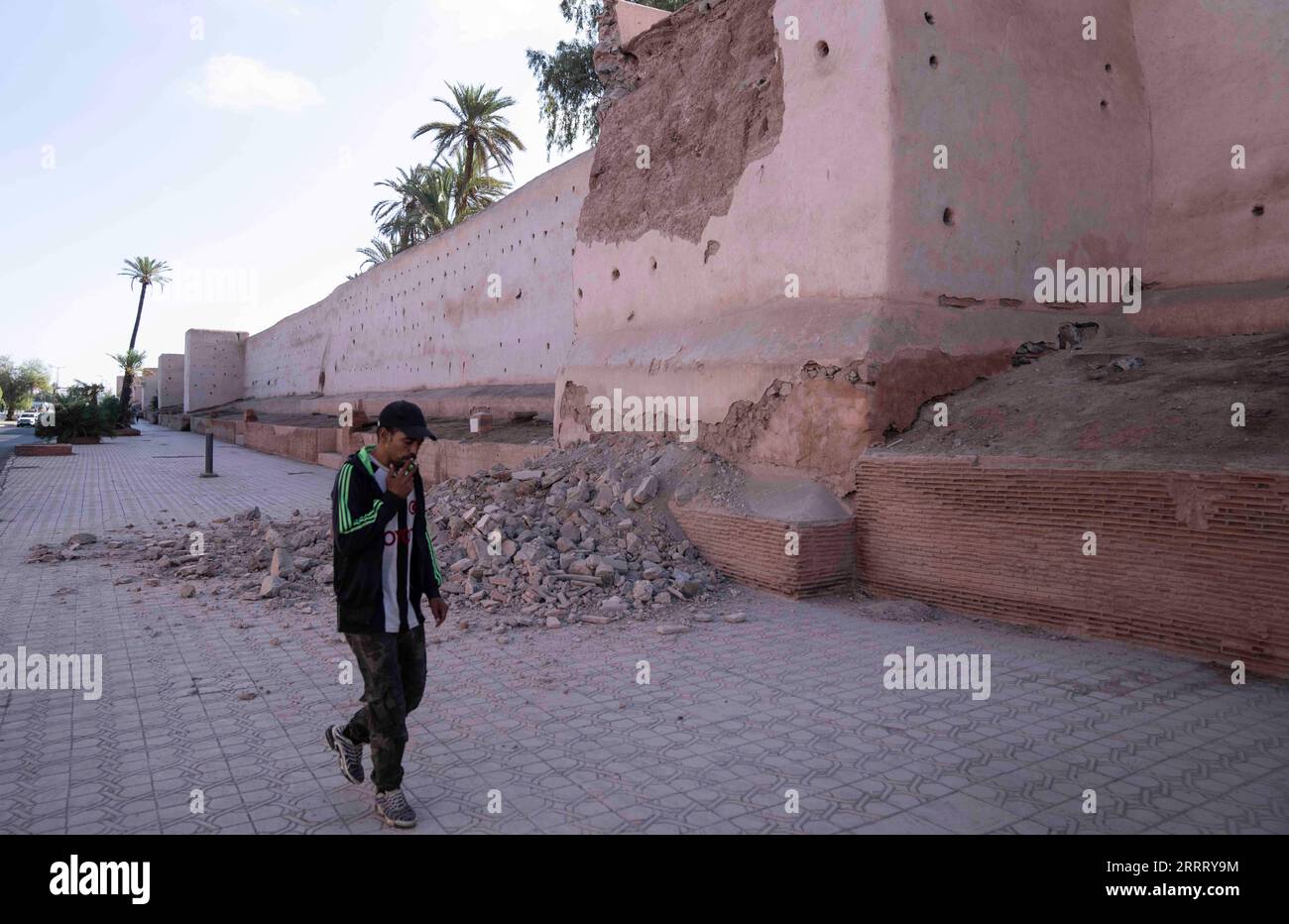 A man walks past a damaged wall of the historic Medina of Marrakech ...