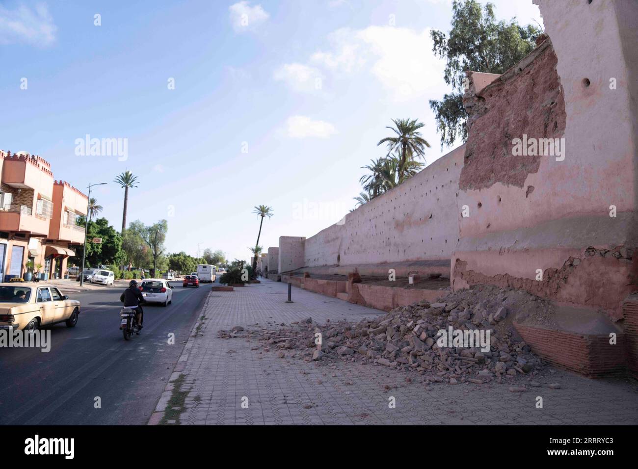 People drive past a damaged wall of the historic Medina of Marrakech ...