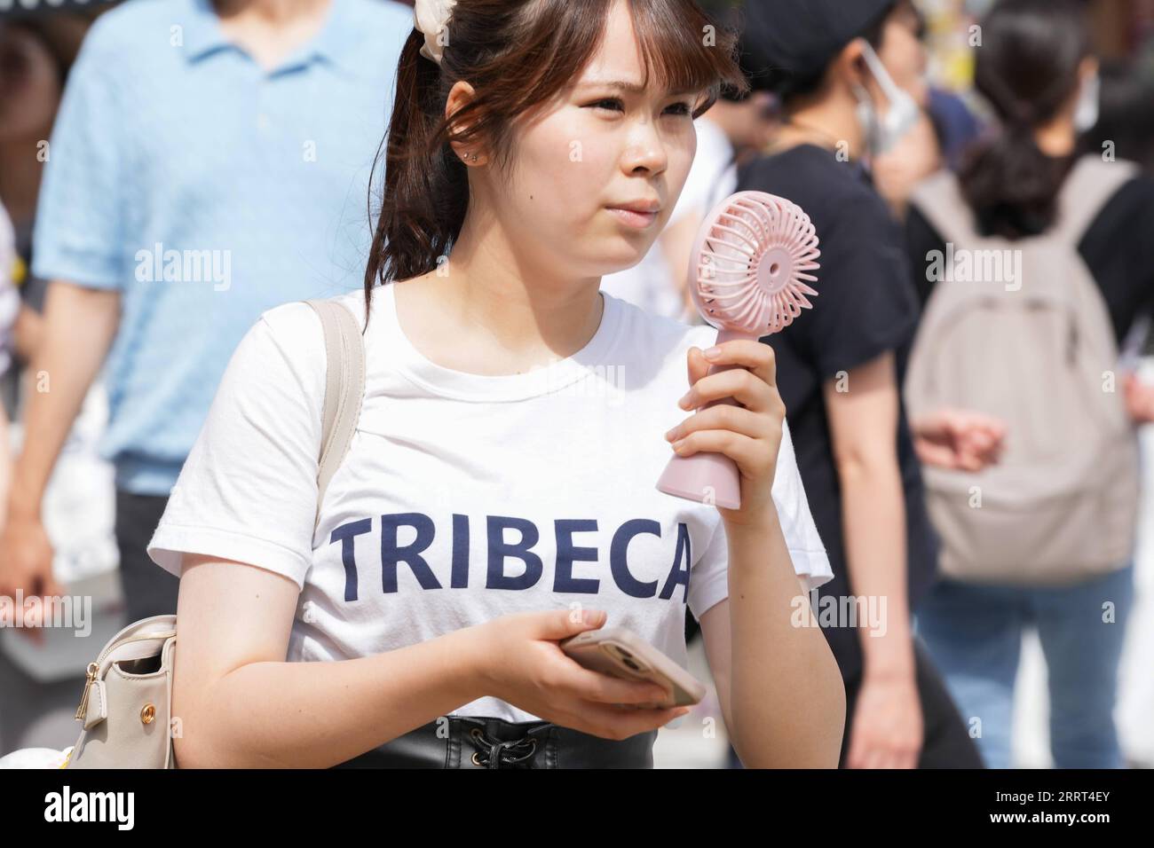 230629 -- TOKYO, June 29, 2023 -- A pedestrian uses a portable fan to ...