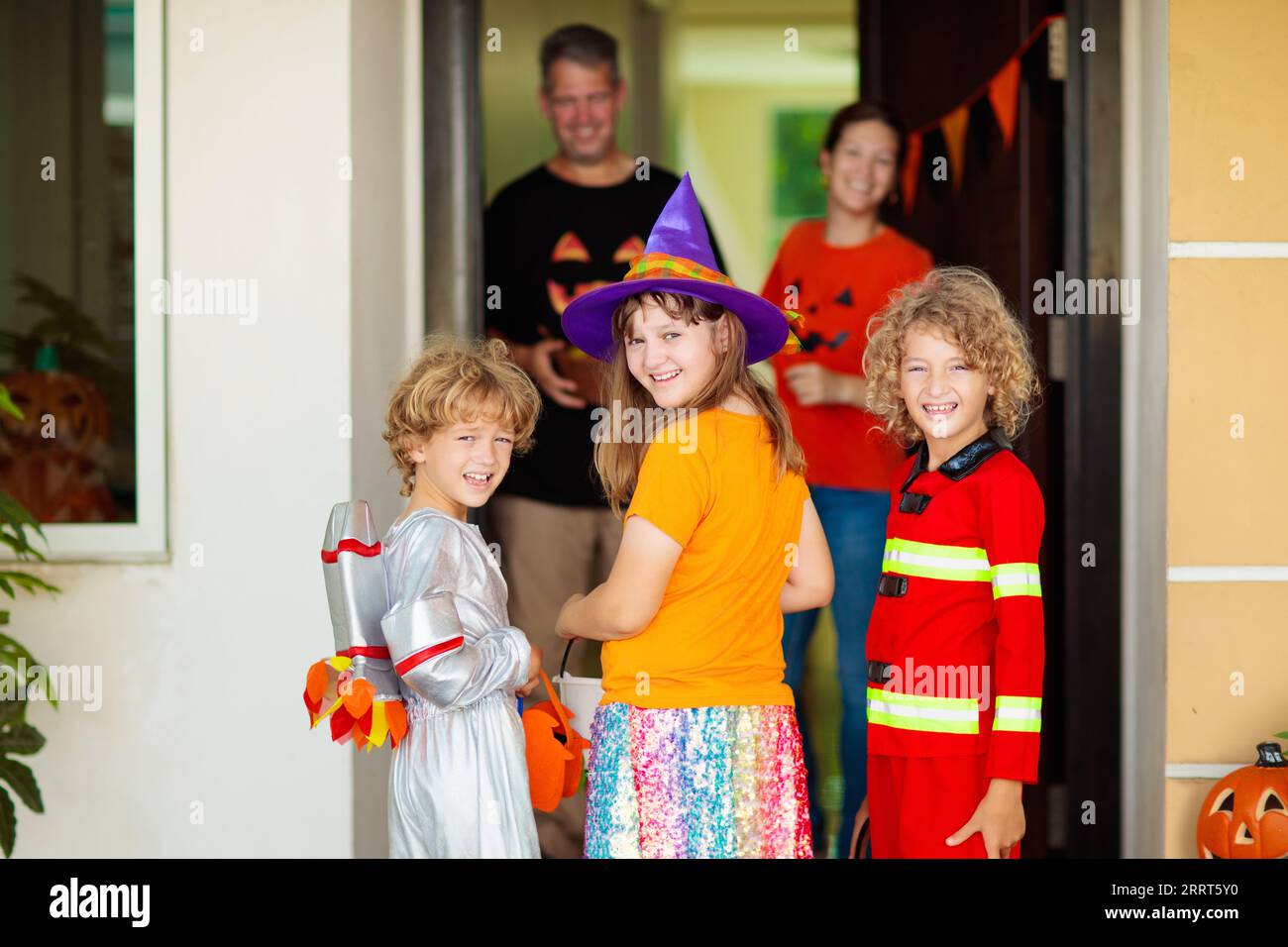 Kids trick or treat on Halloween night. Dressed up children at ...