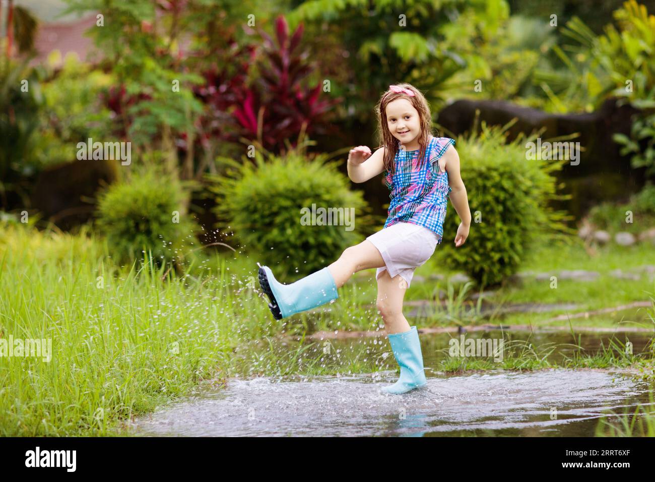 Kid playing out in the rain. Children with umbrella and rain boots play ...