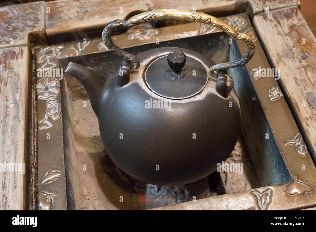 Traditional metal Chinese kettle on coals boiling water for tea. High ...