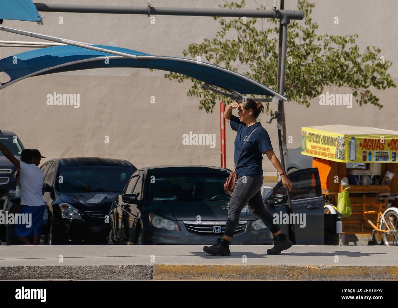 230708 -- CIUDAD JUAREZ, July 8, 2023 -- A woman protects herself from ...