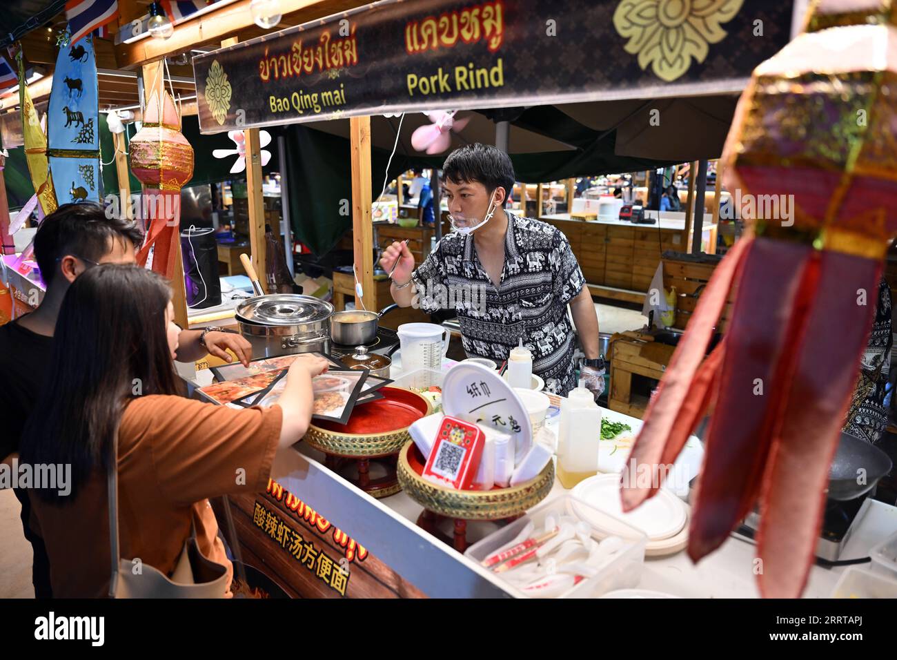 230710 -- HAIKOU, July 10, 2023 -- People buy snacks at a Thai food ...
