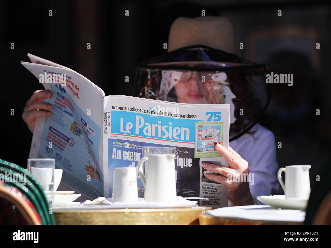 230713 -- PARIS, July 13, 2023 -- A customer reads a newspaper at a ...