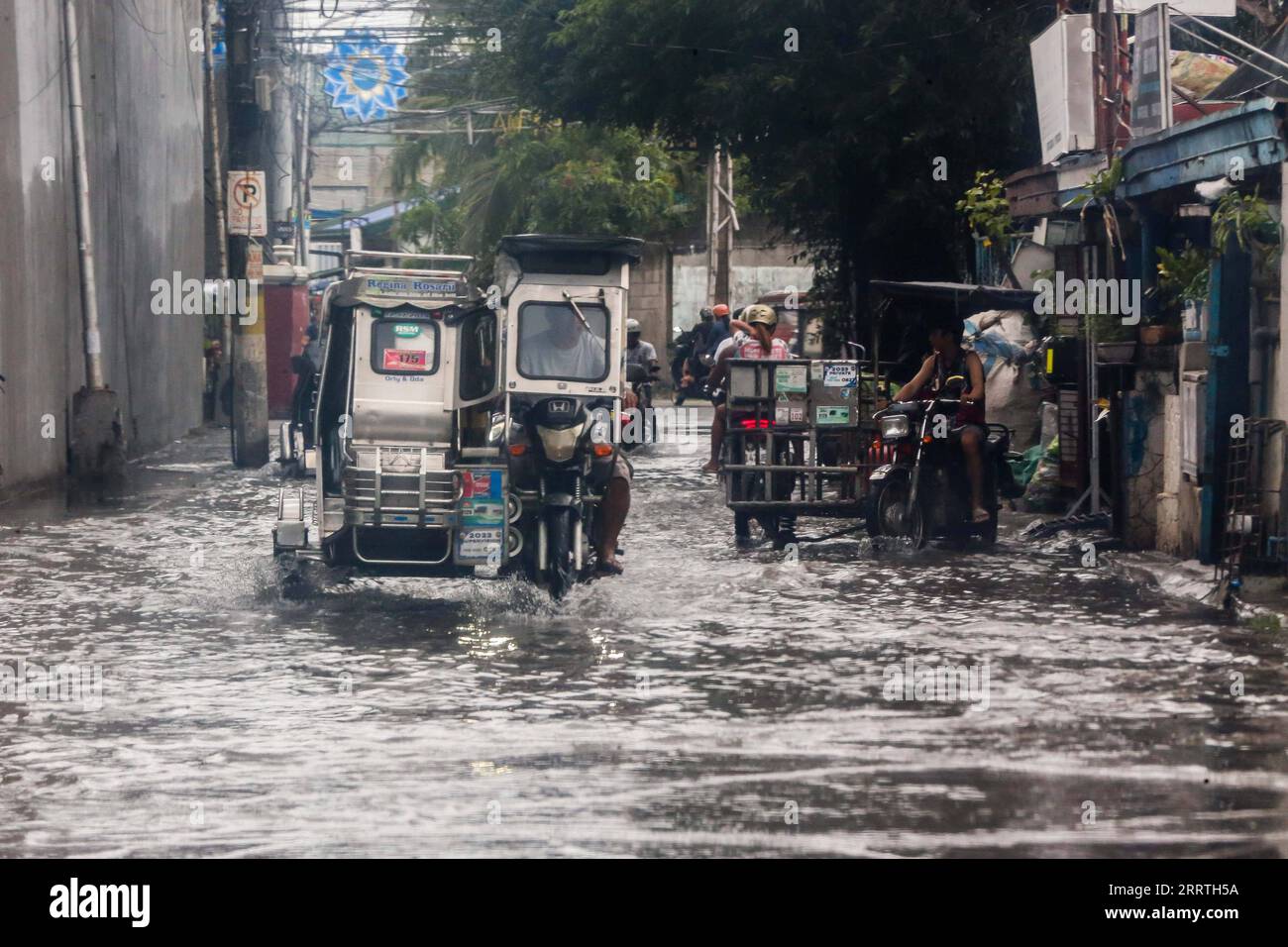 230726 -- MALABON CITY, July 26, 2023 -- People wade through a water ...