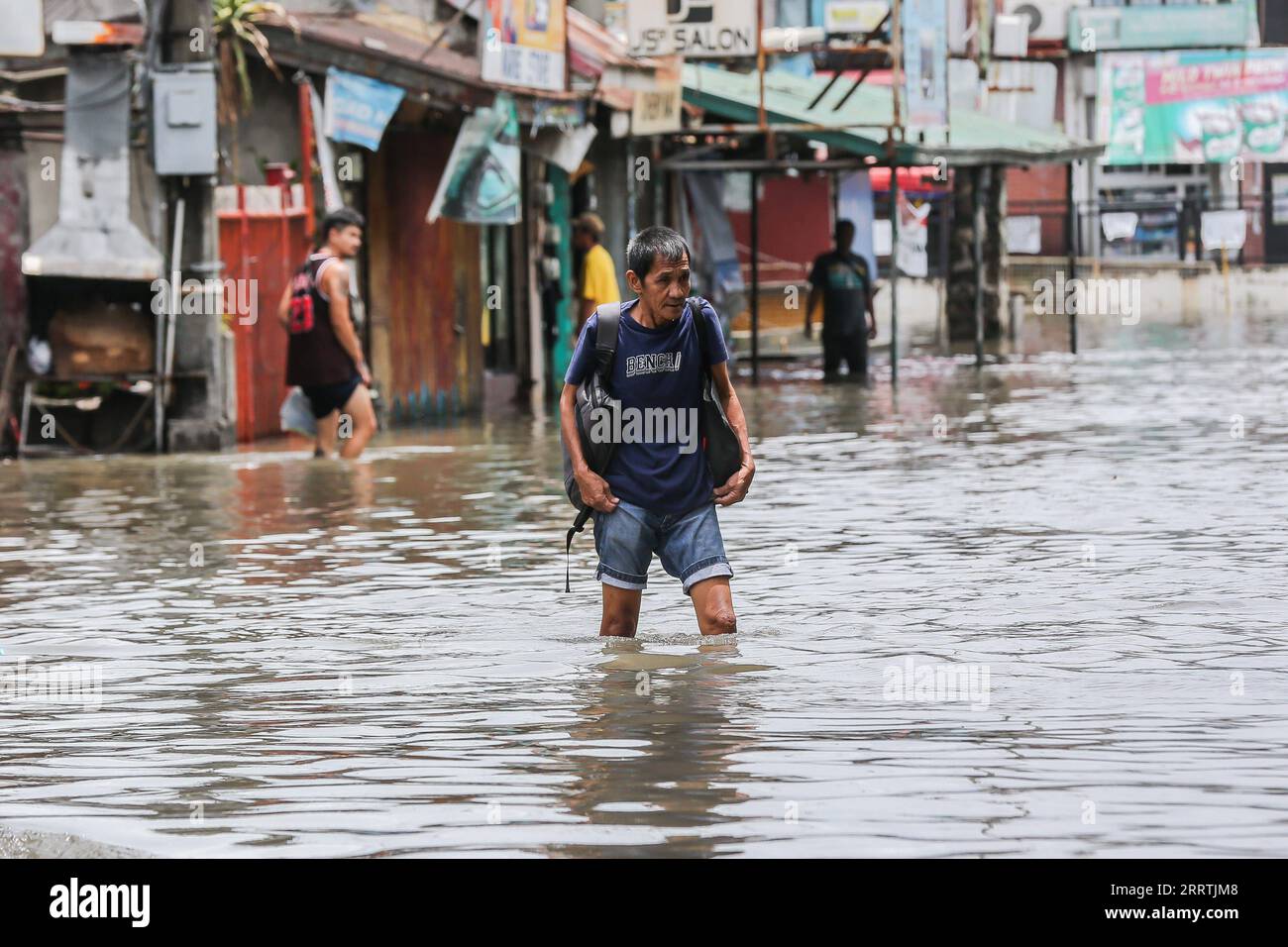230728 -- VALENZUELA CITY, July 28, 2023 -- A man wades through ...