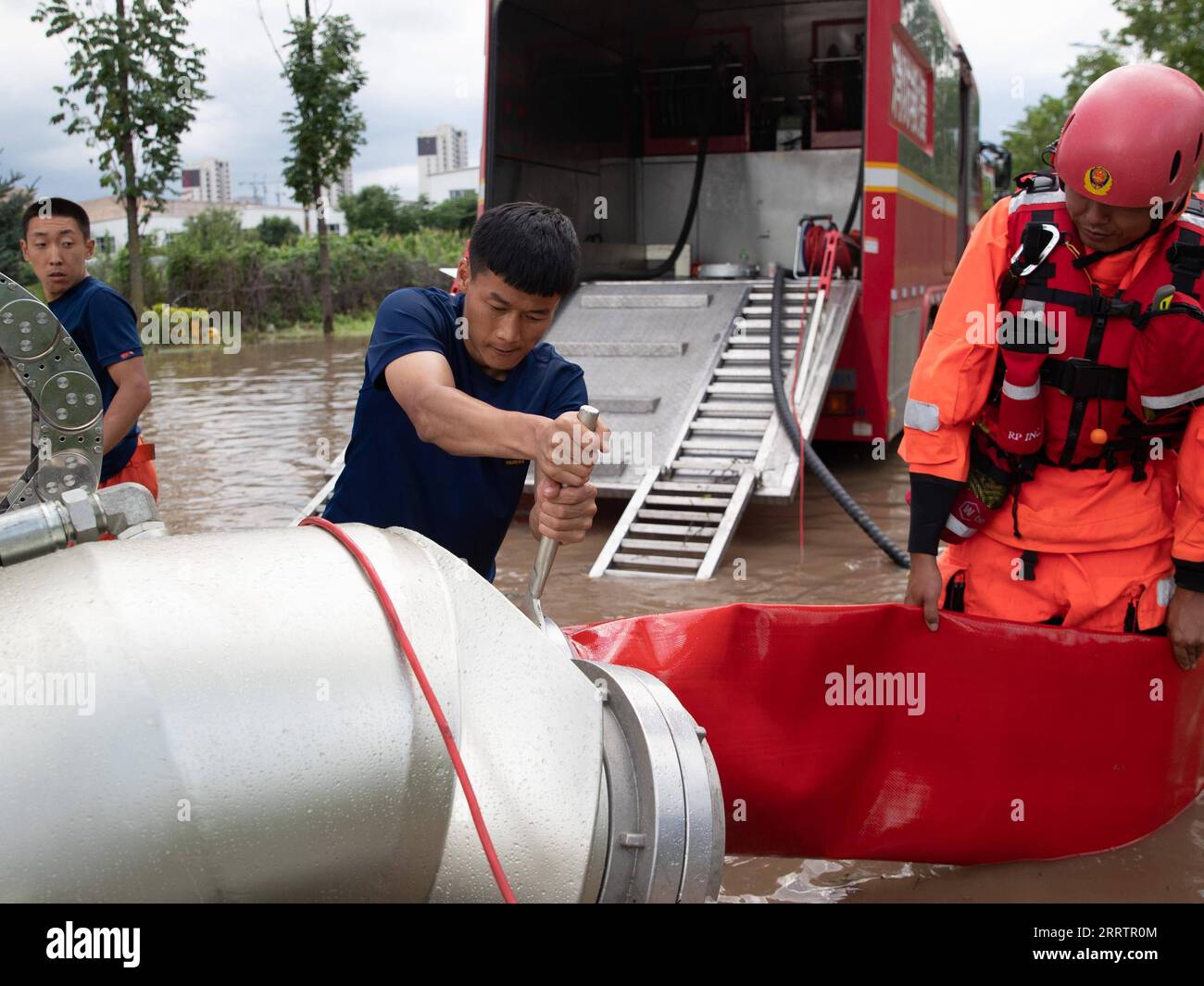 230805 -- HARBIN, Aug. 5, 2023 -- Firefighters install a drainage ...