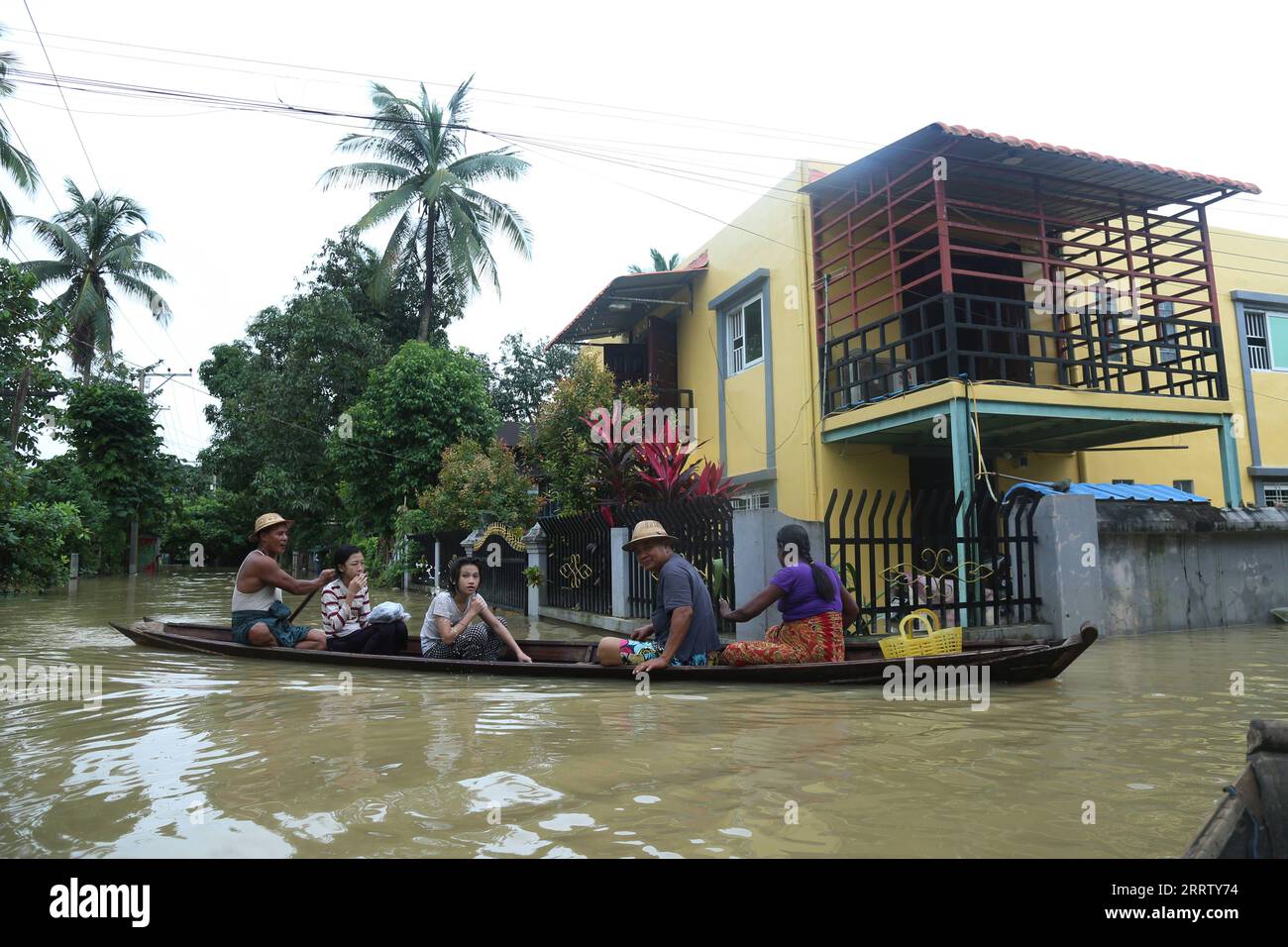 230812 -- BAGO, Aug. 12, 2023 -- People row a wooden boat on flood ...