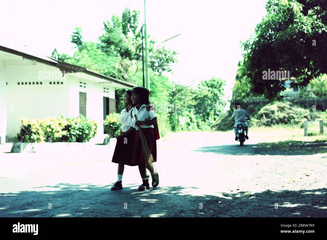 Two cute young school girls together walking hand in hand to school in ...