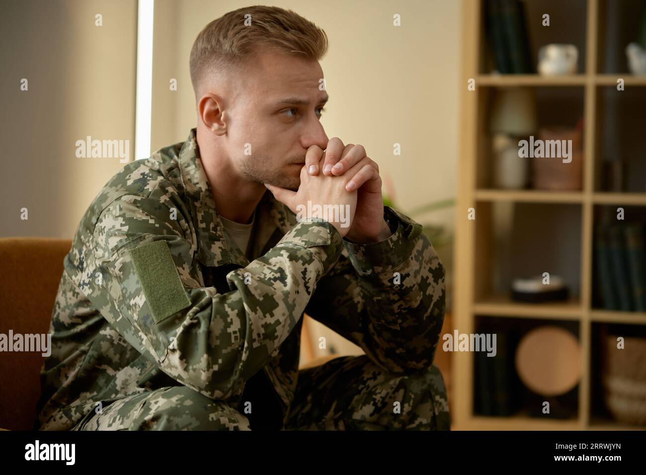 Upset soldier in military uniform thinking worrying about his mental ...