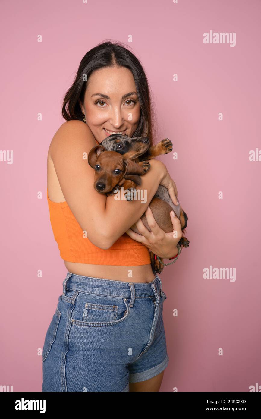 Young woman hugs her puppy Dachshund dogs and looks at them. Love ...