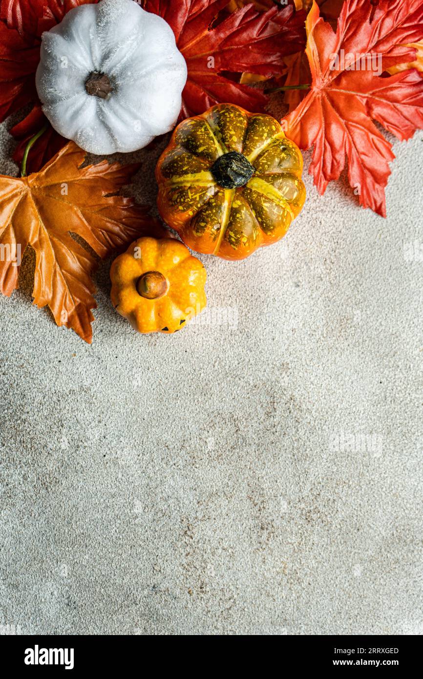 Autumnal frame made with artificial maple leaves and pumpkins on stone ...