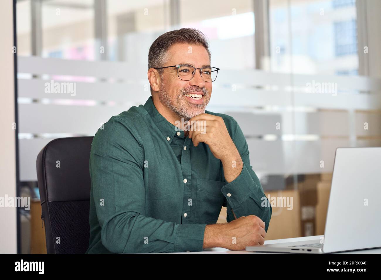 Happy Indian older business man sitting at work desk in office with ...