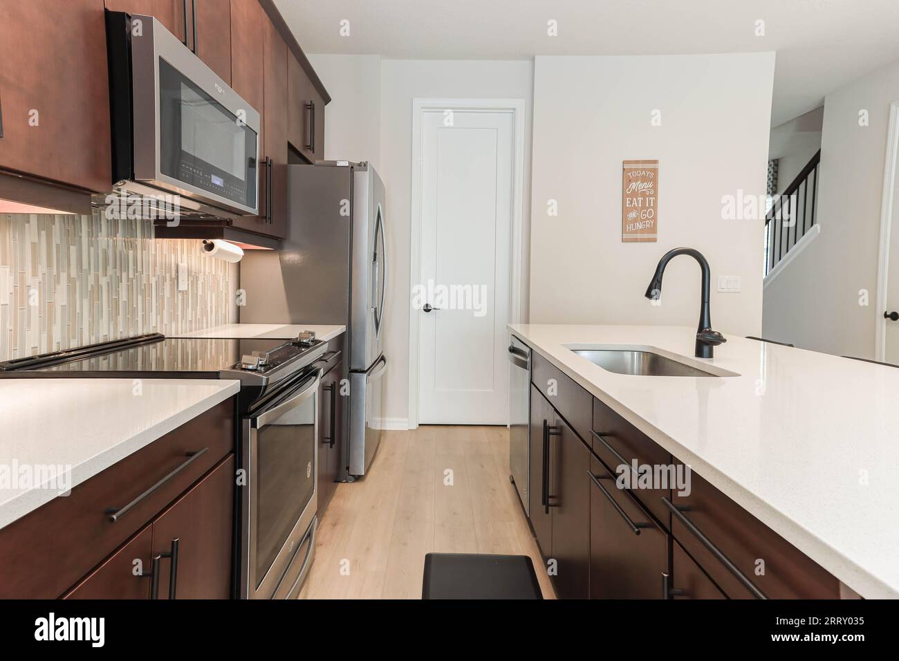 A modern kitchen featuring dark wood cabinets, a white marble ...