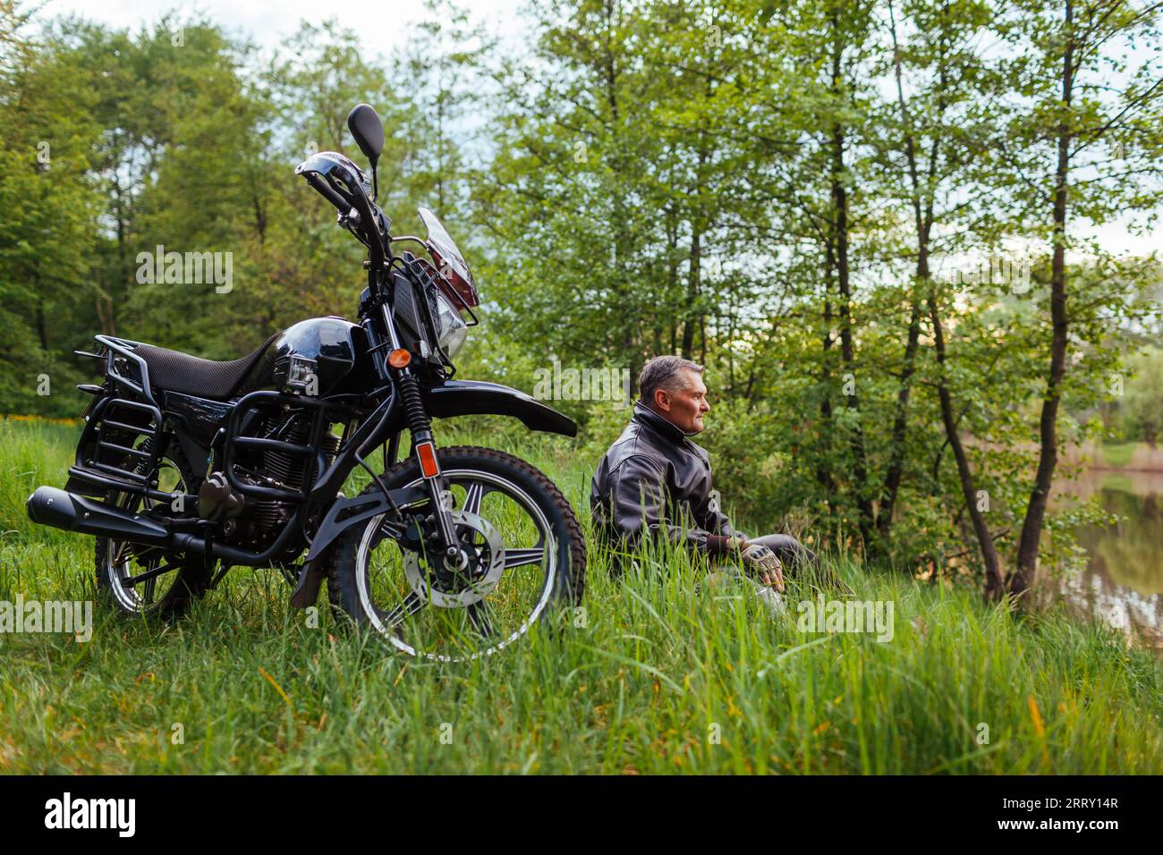 Senior biker relaxing by motobike outdoors. Man wearing leather jacket ...