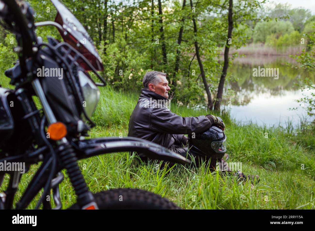 Portrait of senior biker relaxing by motobike outdoors. Man wearing ...
