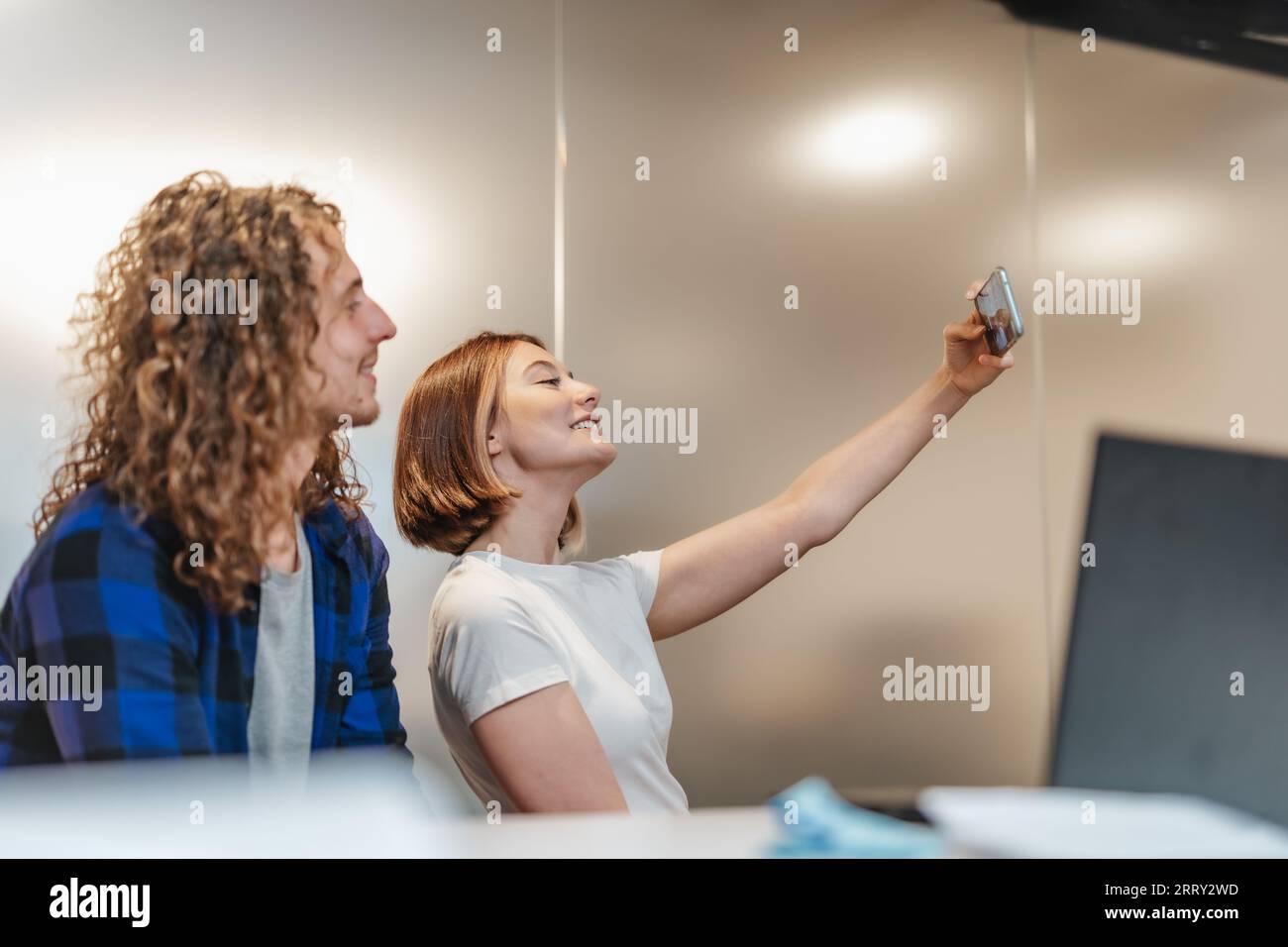 Side view shot of couple taking a selfie at work. Short haired girl ...