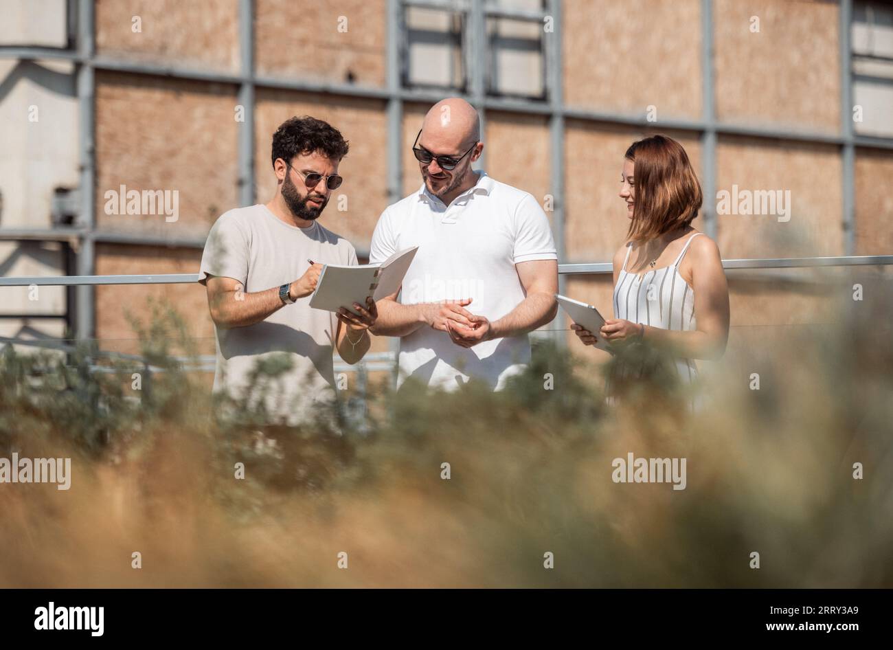 Architectural team discussing blueprint outdoors. Collaborative teamwork for modern building ...