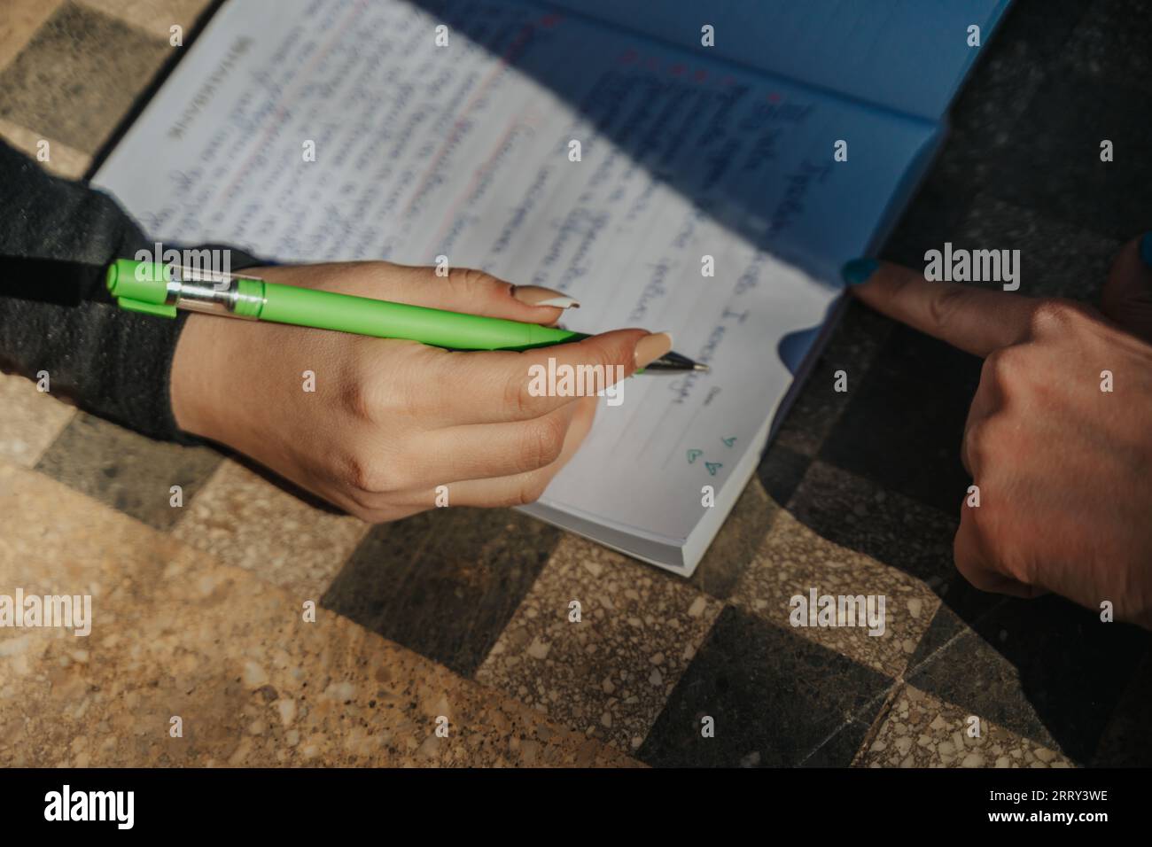 Close up shot of girl with pen in her hand about to write in notebook ...