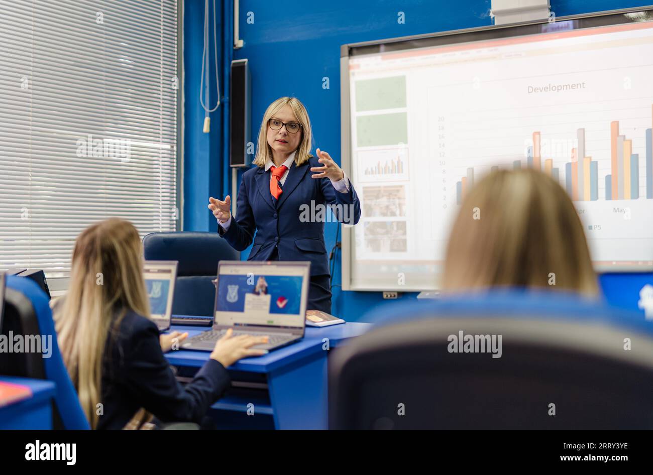 Well-dressed professor giving a lecture to her students about graphs ...