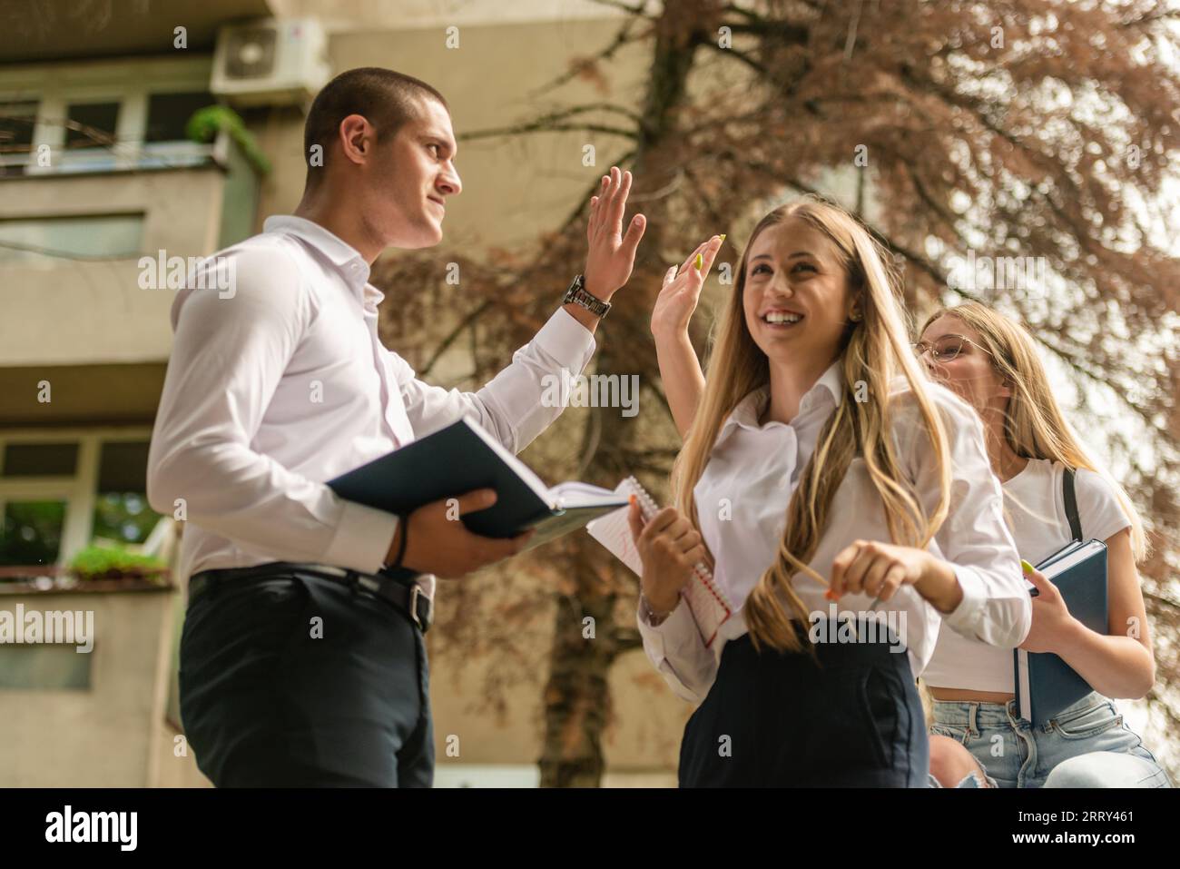 Happy students smiling and giving each other high fives outside with ...