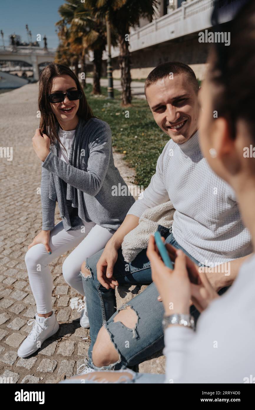 Close up of three friends sitting, smiling and talking at the sunny ...
