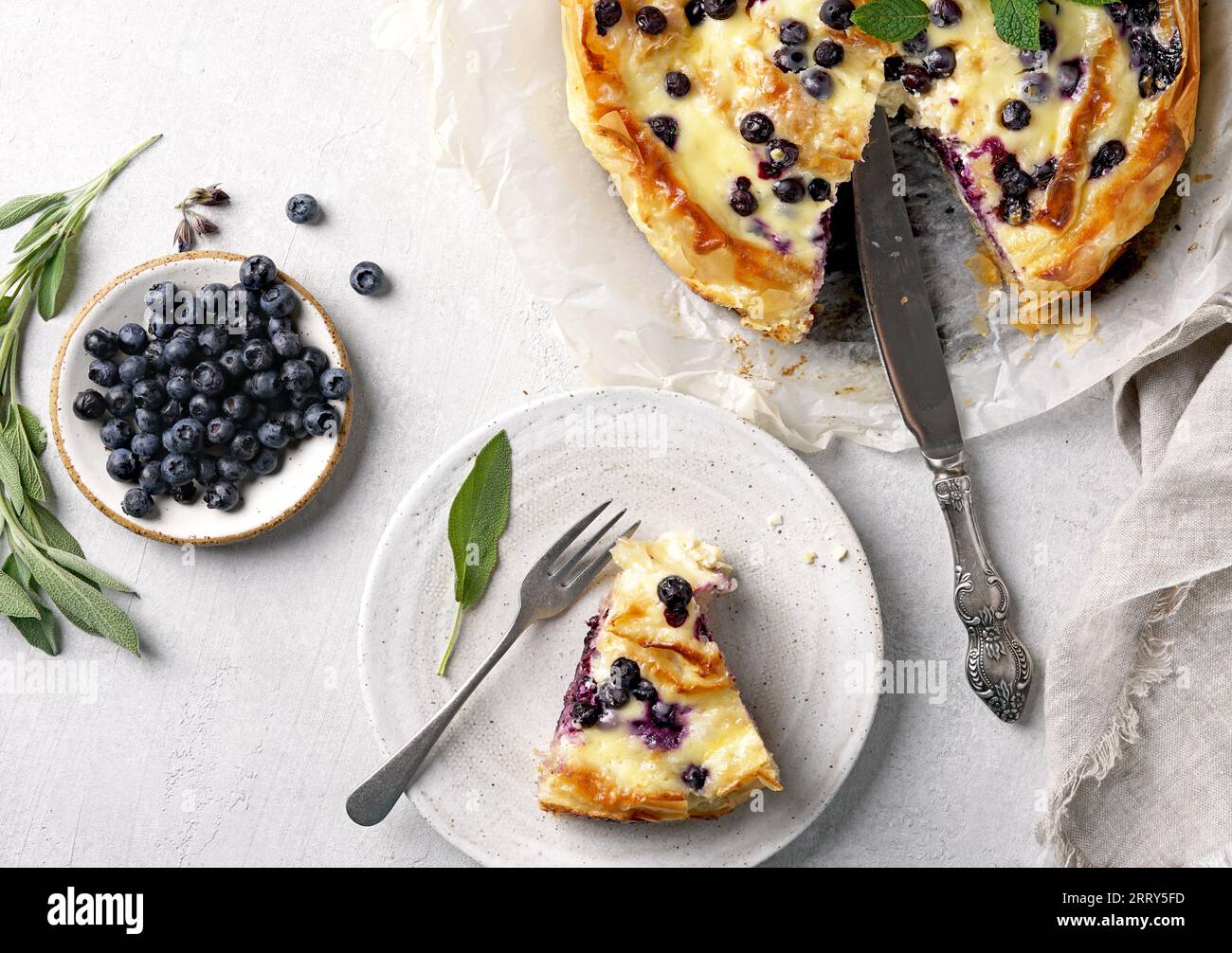 Layered Blueberry Pie With Phyllo Crust and cream on a light table with ...