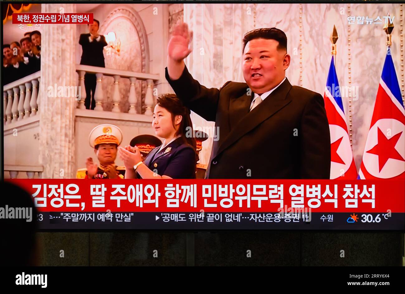 A TV screen shows the North Korean leader Kim Jong Un (R) waving and ...