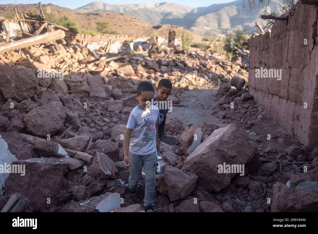 Moroccan boys, Rayan and Ali walk amidst the rubble of their home which ...